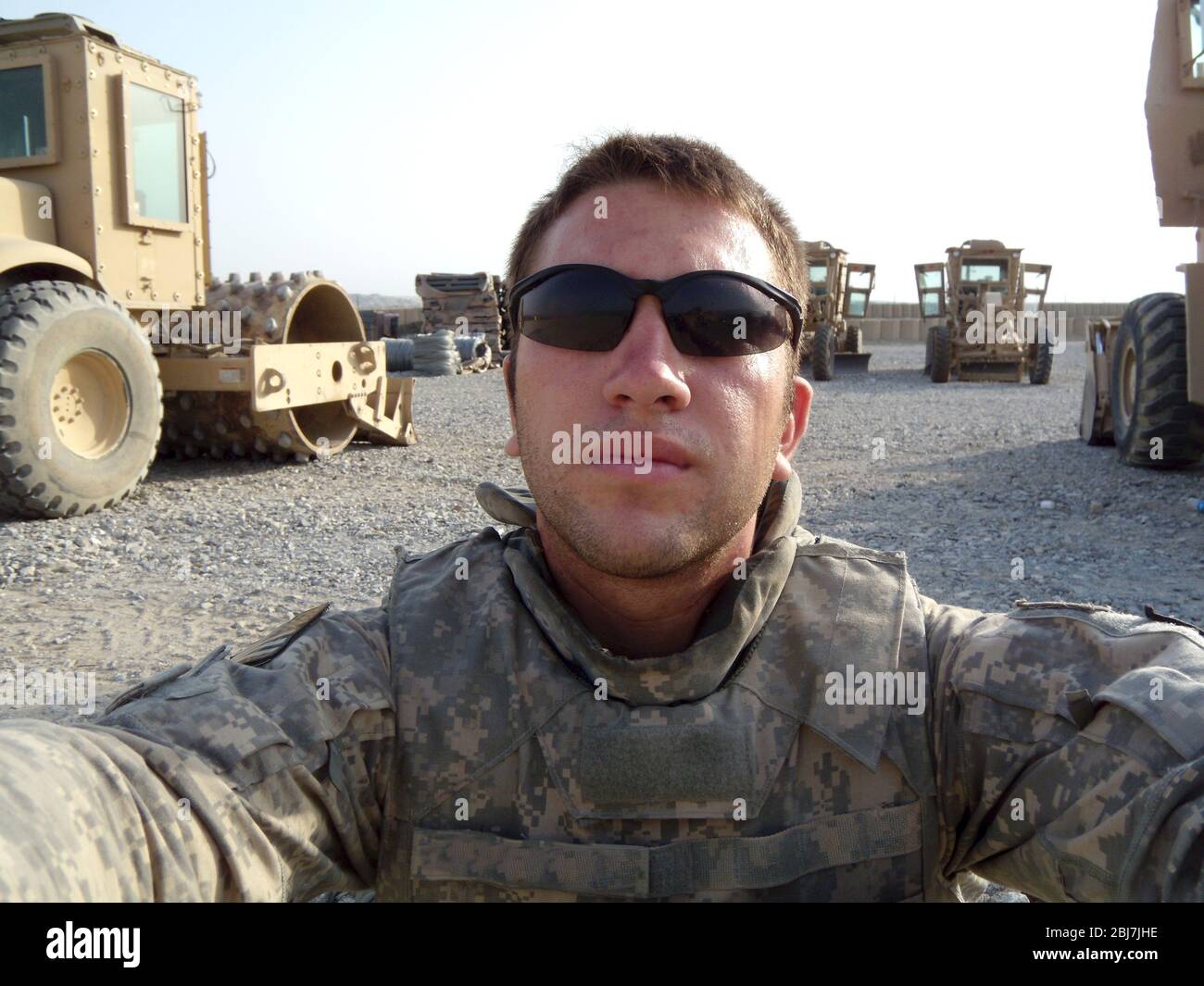 Young soldier sits with heavy equipment machines, tools of the job he ...