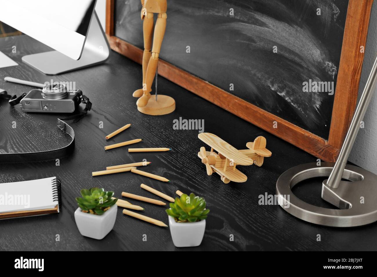 Desktop with computer monitor and other items on blackboard background ...