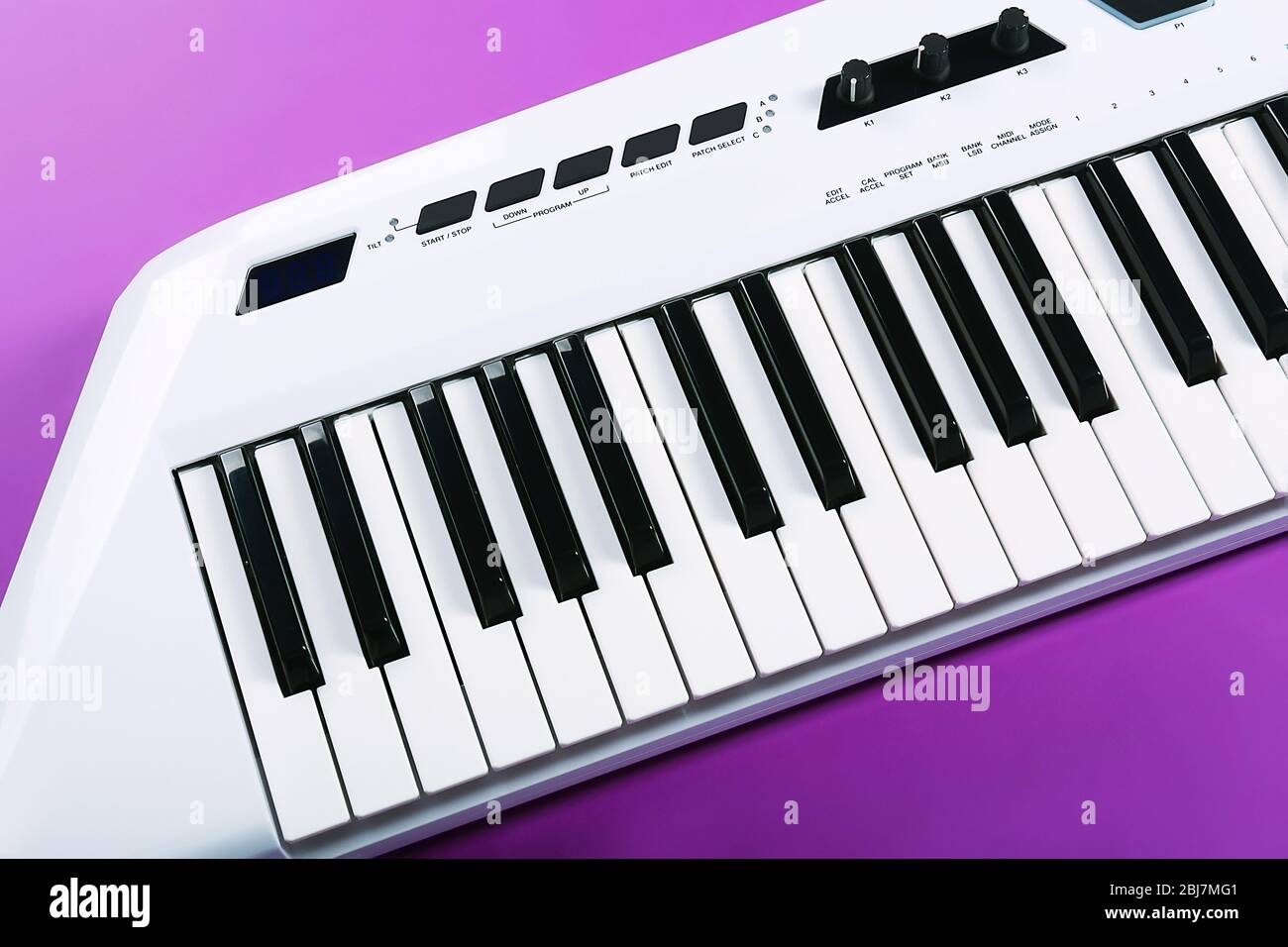 Keyboard of synthesizer on purple background Stock Photo - Alamy