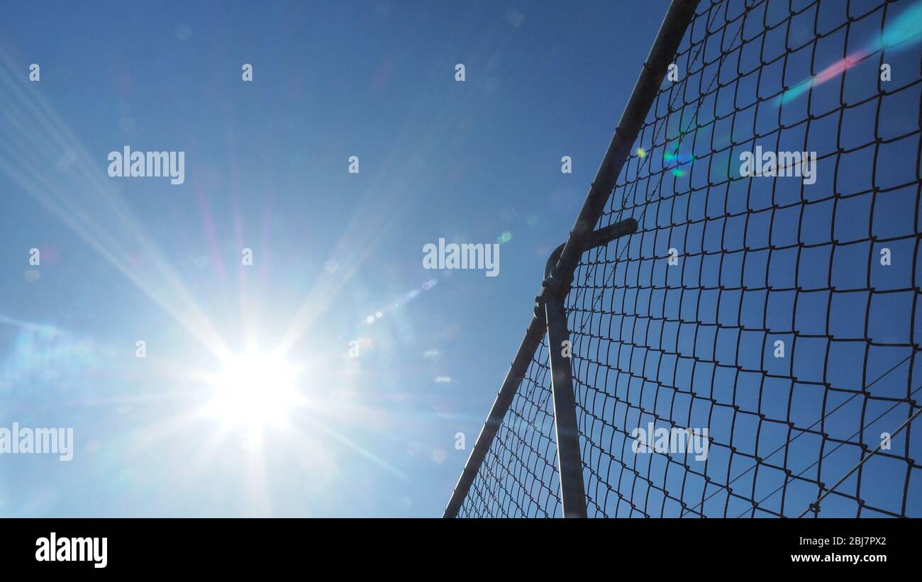 Cyclone fence with sun flare Stock Photo - Alamy