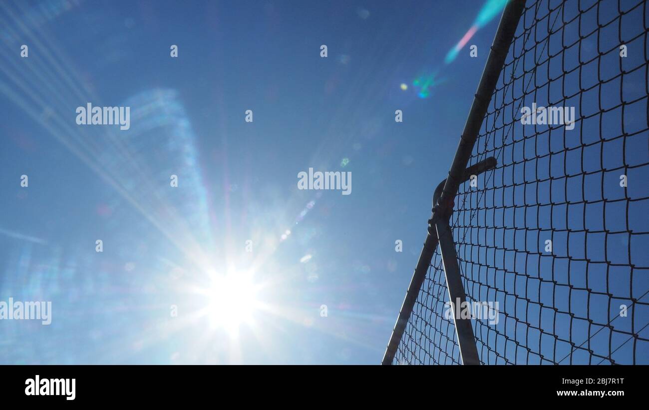 Cyclone fence with sun flare Stock Photo - Alamy
