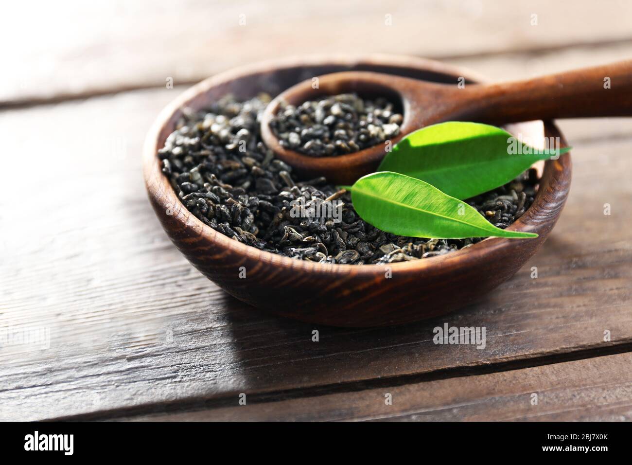 Granulated tea with green leaves in wooden bowl on table closeup Stock ...