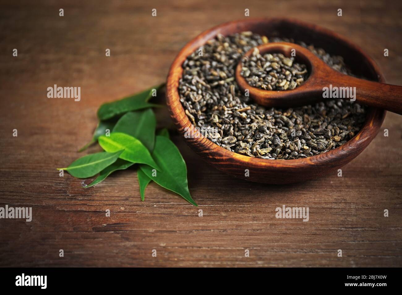 Granulated tea with green leaves in wooden bowl on table closeup Stock ...