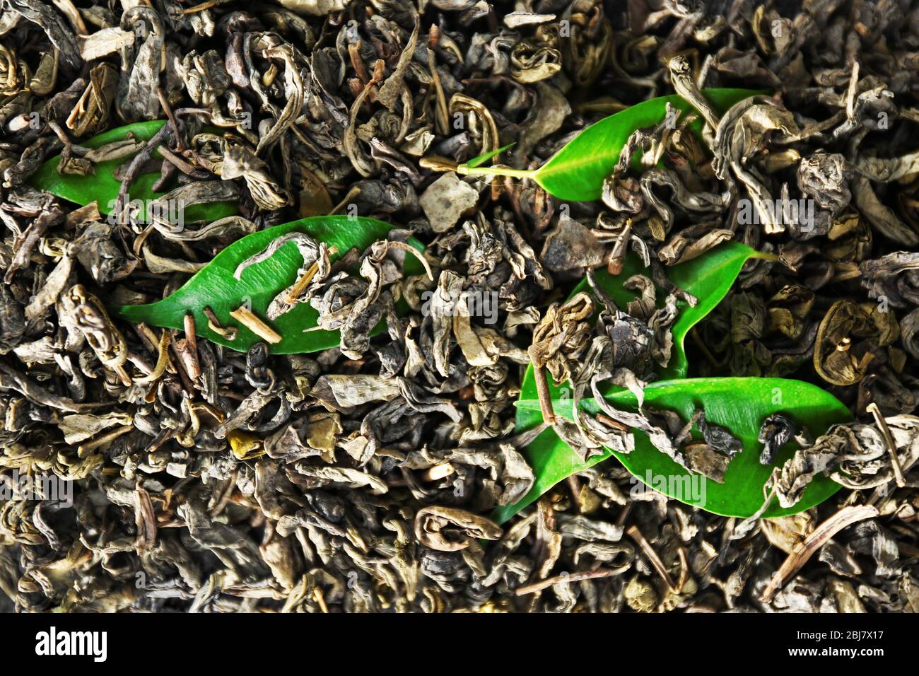Granulated tea with green leaves as background Stock Photo - Alamy