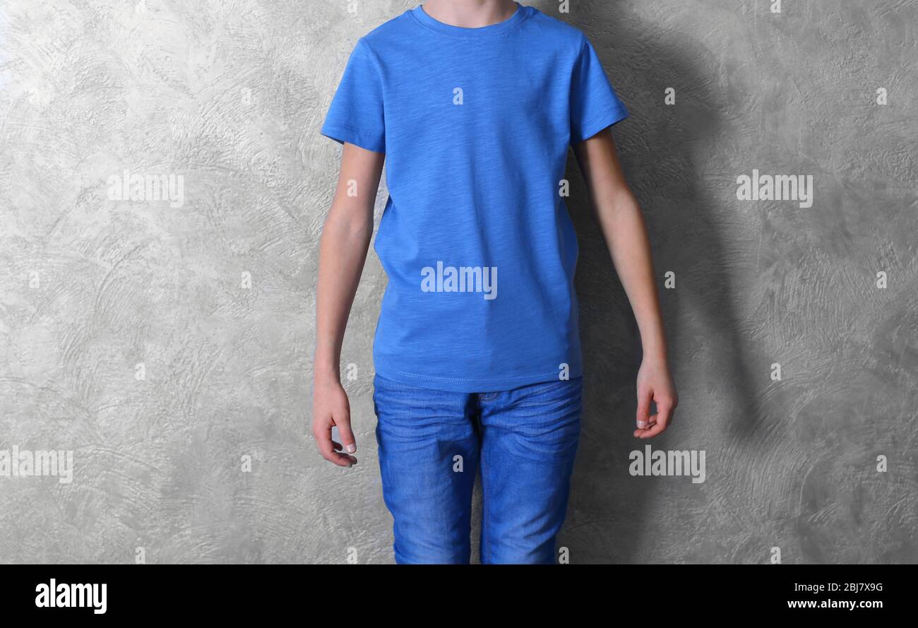 Clothes advertising. Boy in blue T-shirt and jeans against grey ...