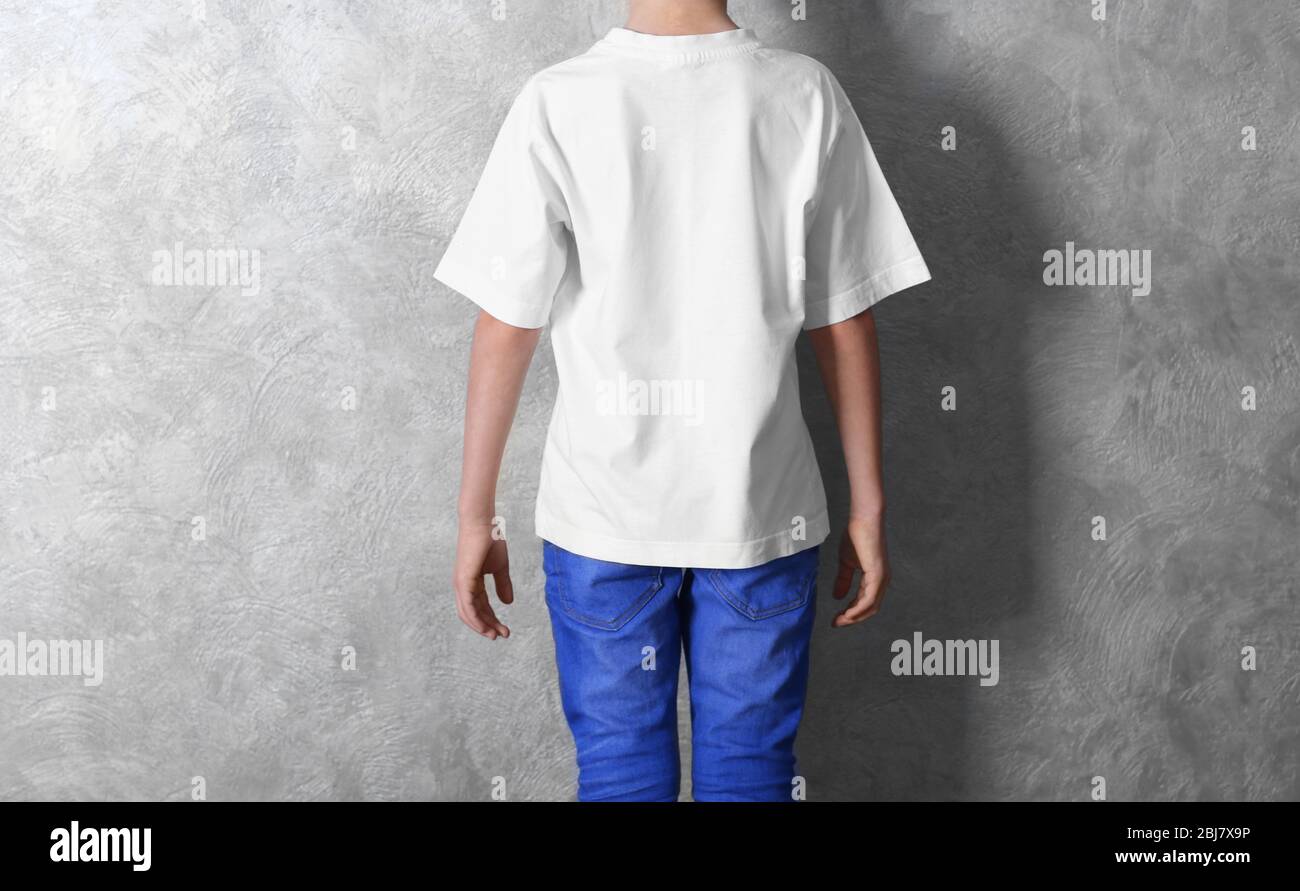 Clothes advertising. Boy in white T-shirt and jeans against grey ...
