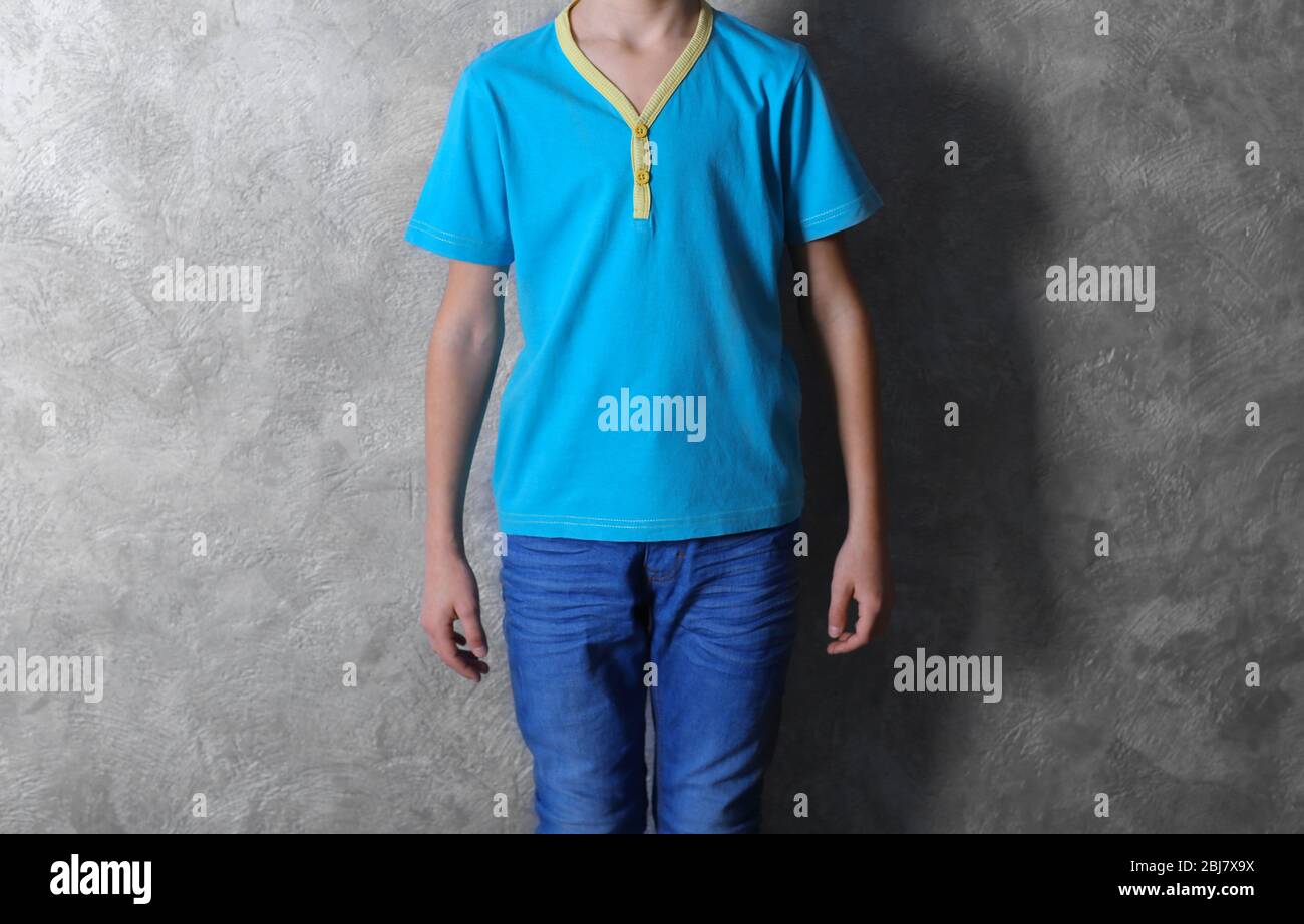 Clothes advertising. Boy in blue T-shirt and jeans against grey ...