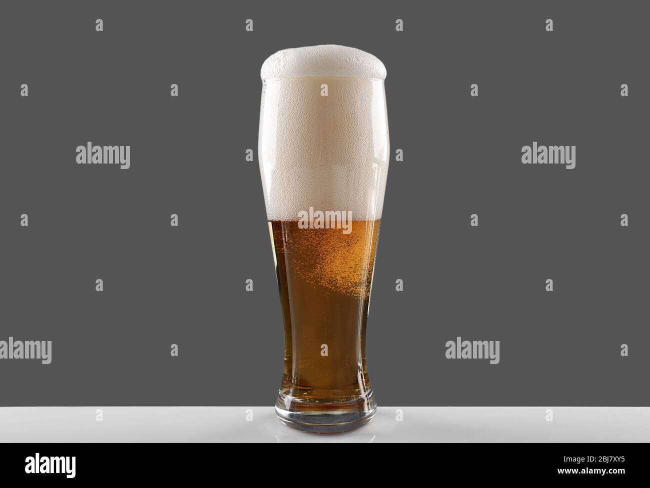 Glass of draft lager beer with thick froth on grey background Stock ...