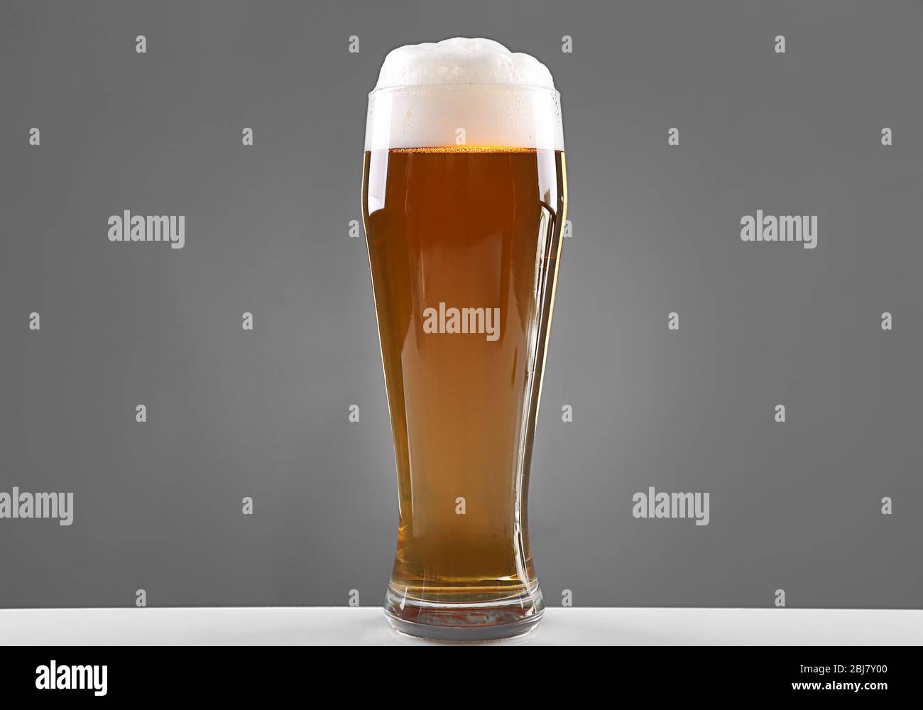 Glass of lager beer with thick froth on grey background Stock Photo - Alamy
