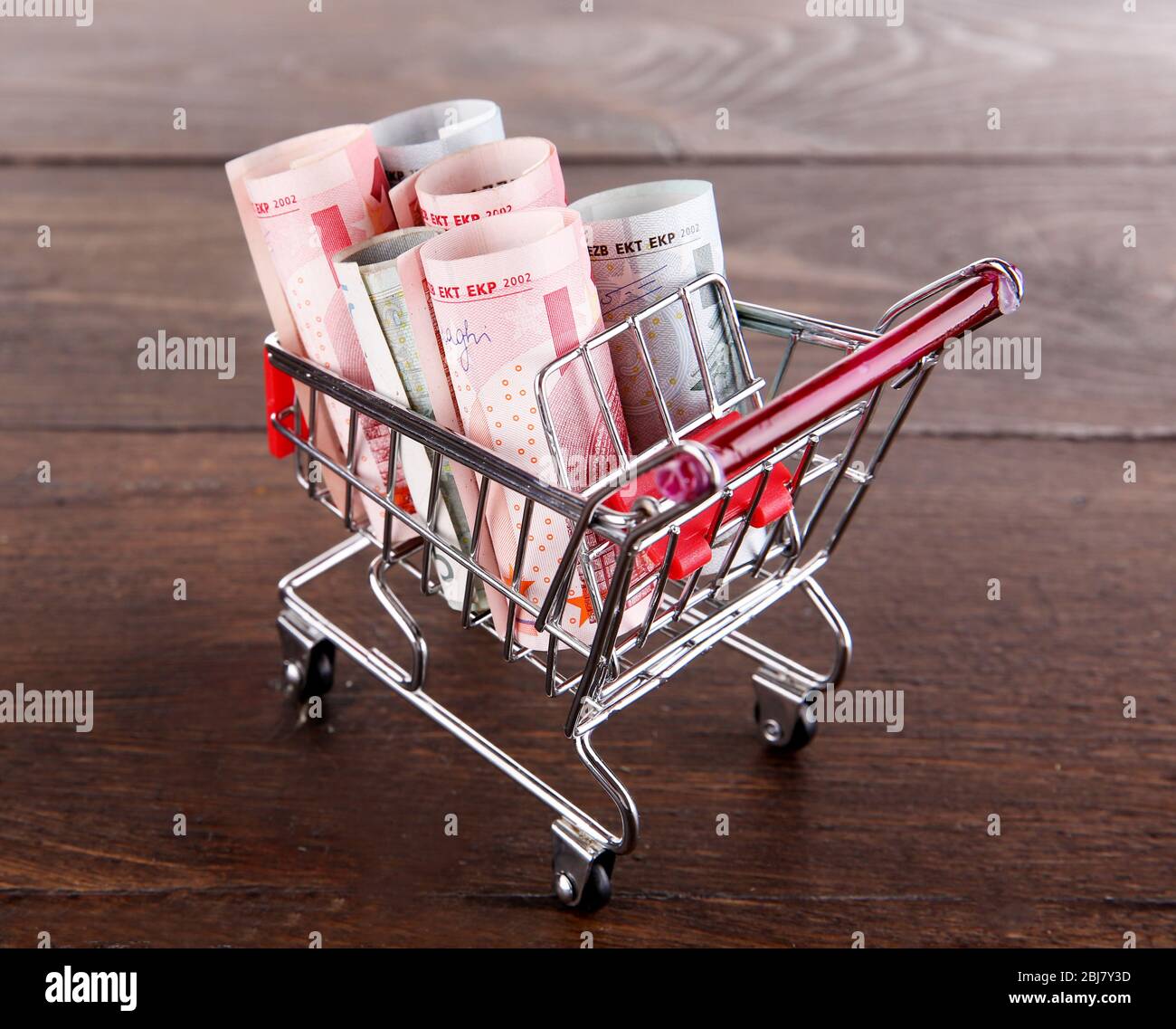 Small shopping trolley with euros banknotes on wooden background Stock ...