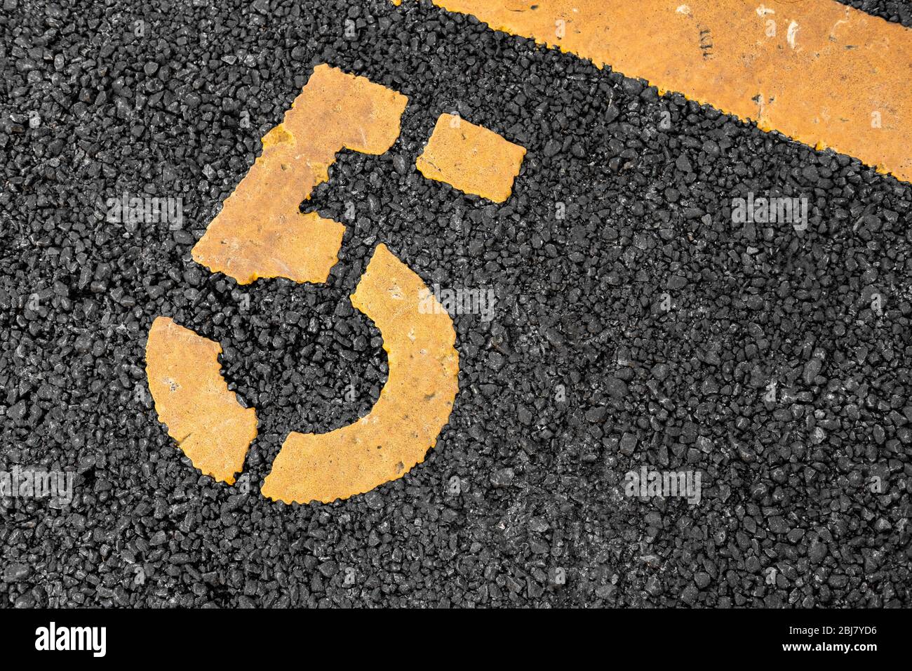 Asphalt parking lot with yellow lot line and yellow lot number 5, five ...