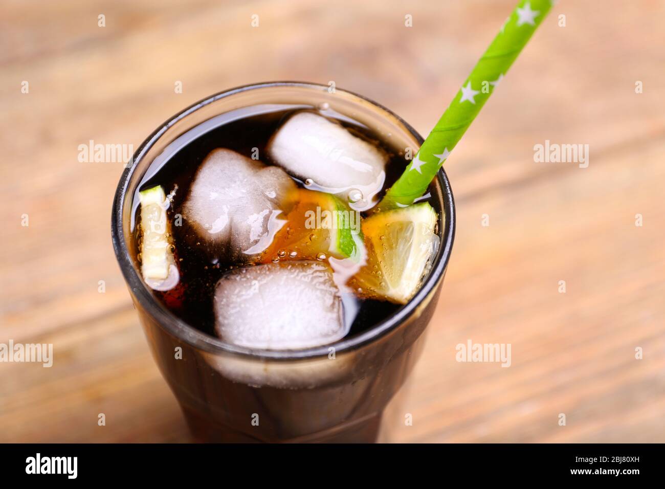 Cocktail with lime slices and ice blocks on wooden table, close up ...