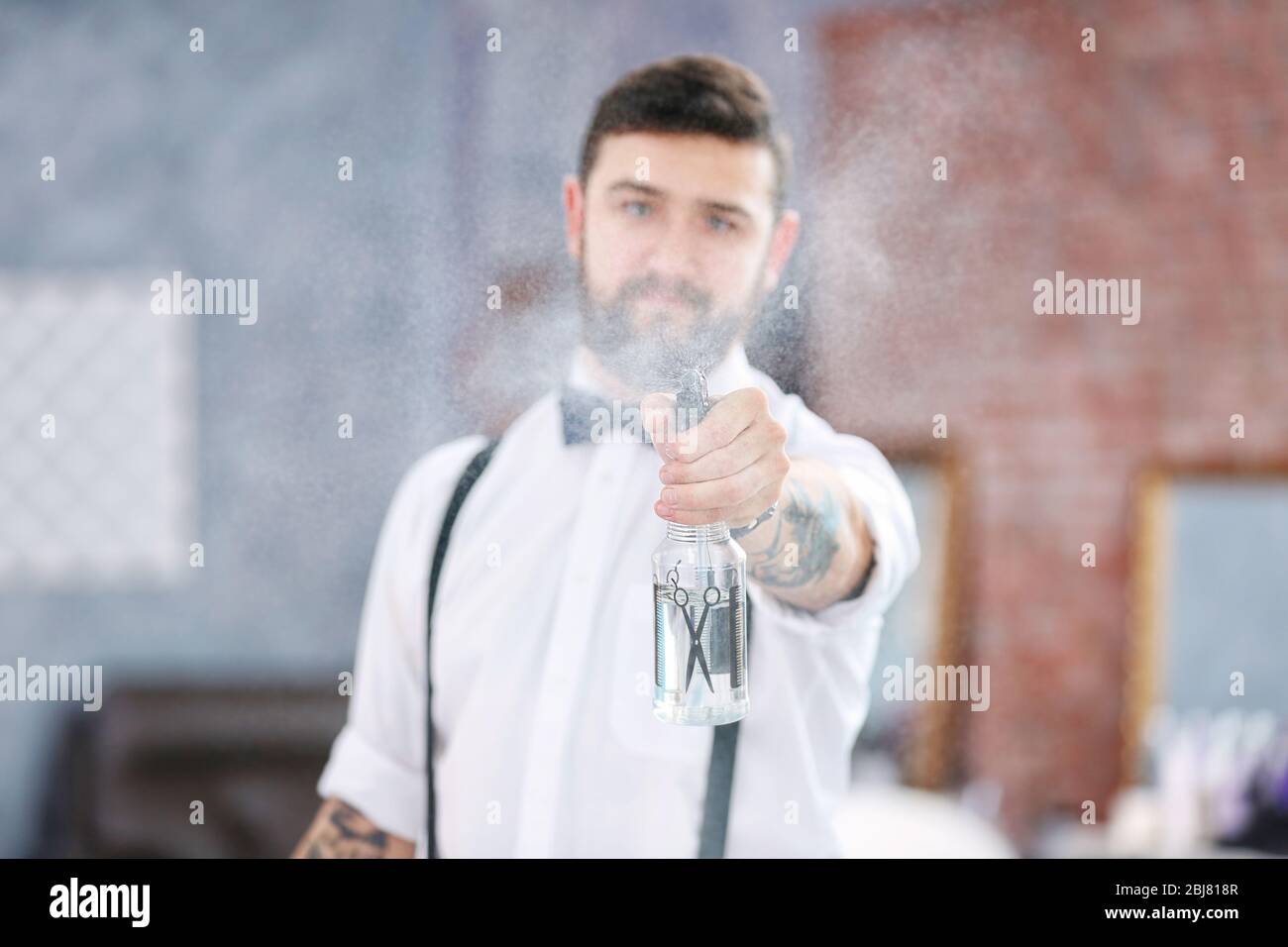 Stylish barber with spray Stock Photo - Alamy