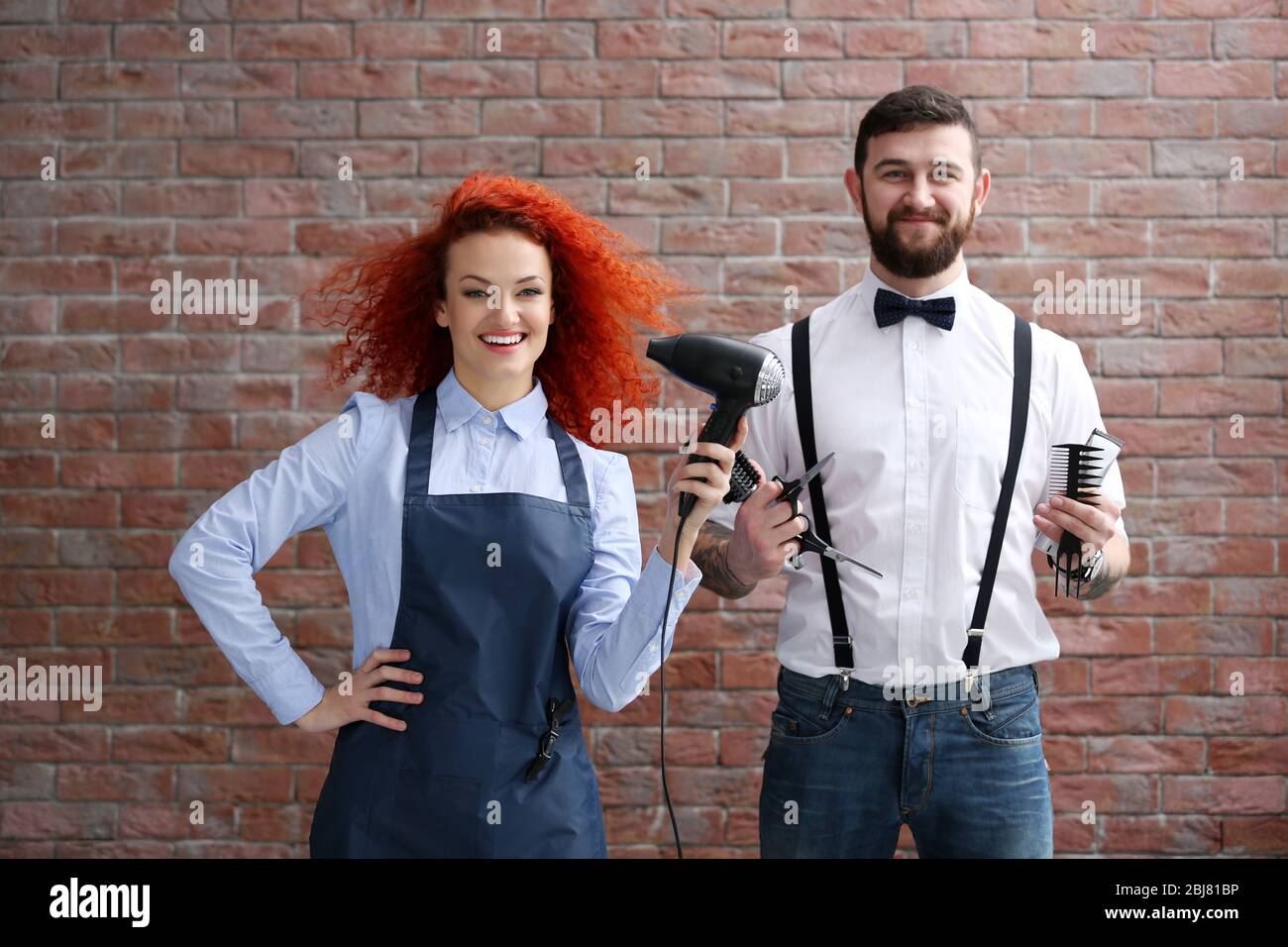 Two professional hairdressers on brick wall background Stock Photo - Alamy
