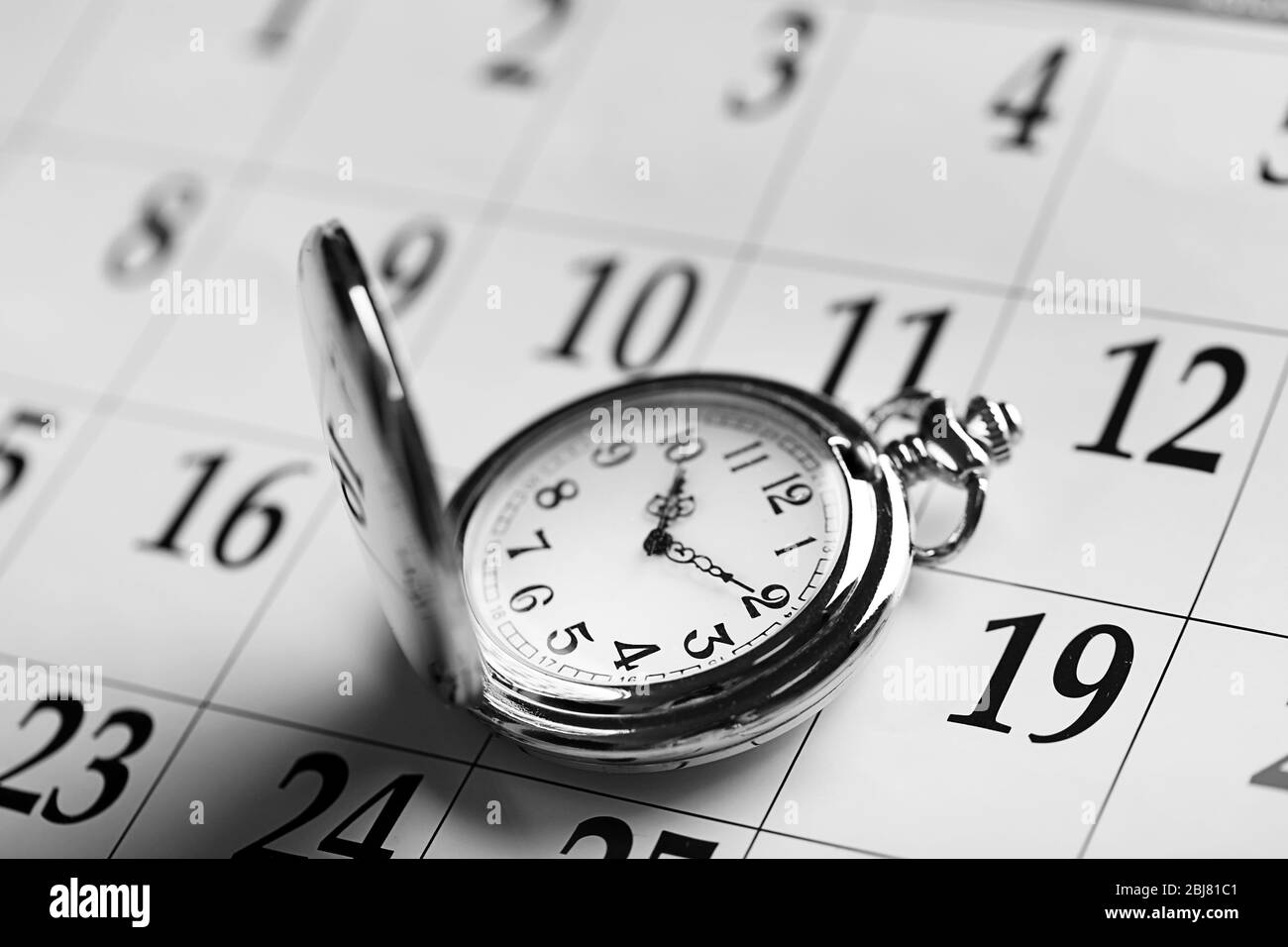 Vintage silver pocket watch laying on calender page with dates, close ...