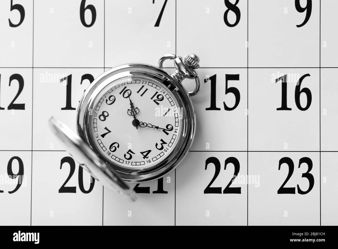 Vintage silver pocket watch laying on calender page with dates, top ...