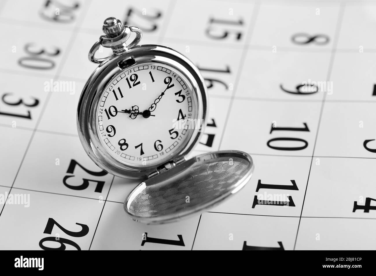 Vintage silver pocket watch laying on calender page with dates, close ...