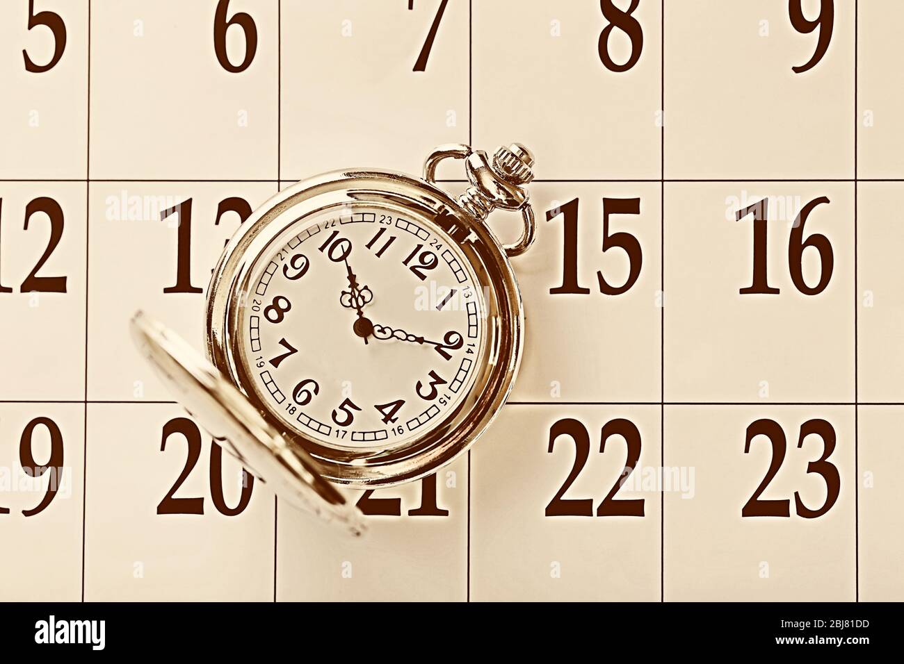 Vintage silver pocket watch laying on calender page with dates, top ...