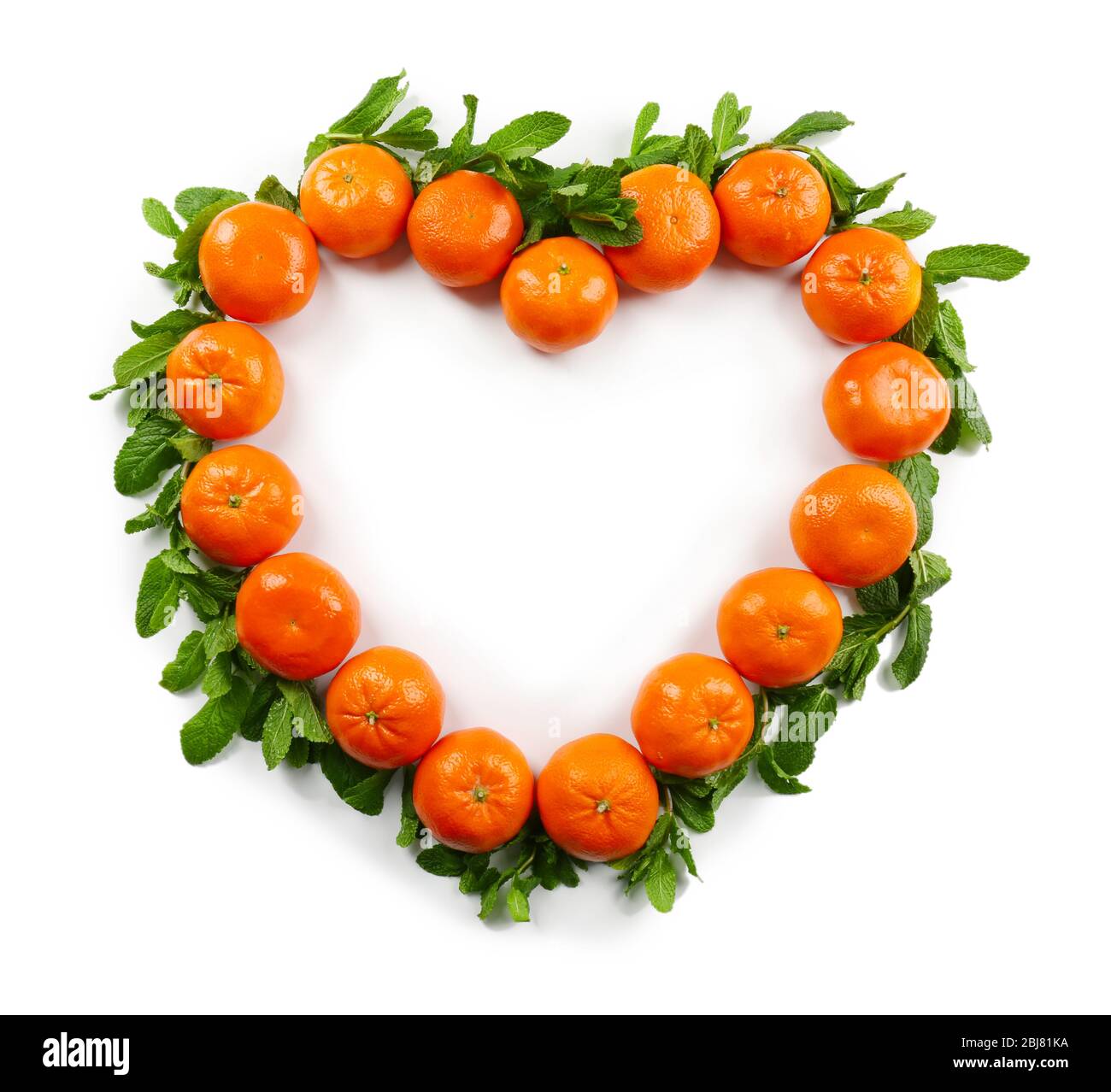 Colorful orange tangerines positioned in a heart shape with mint sprigs ...