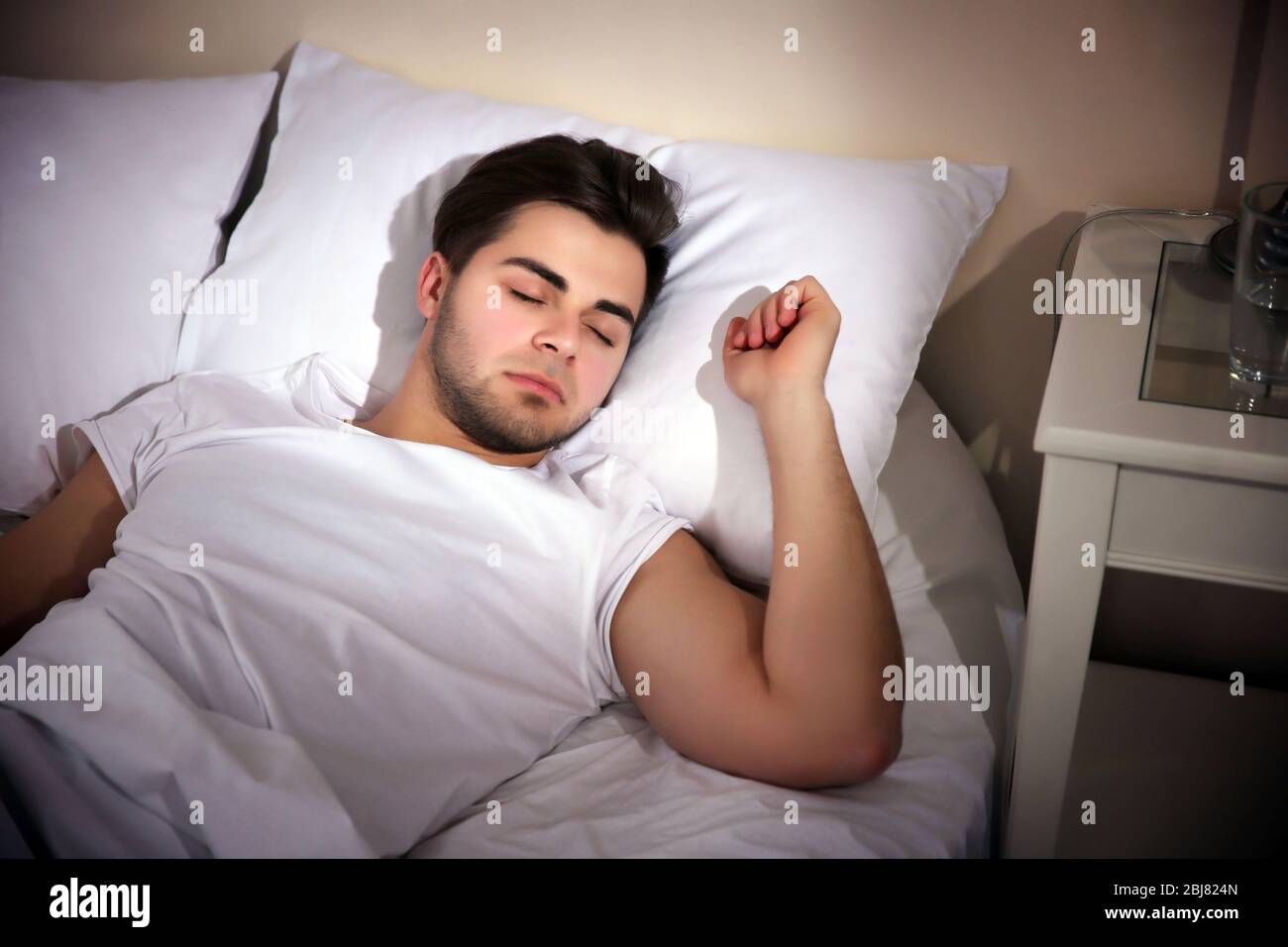 Young man sleeping in bed at night Stock Photo - Alamy