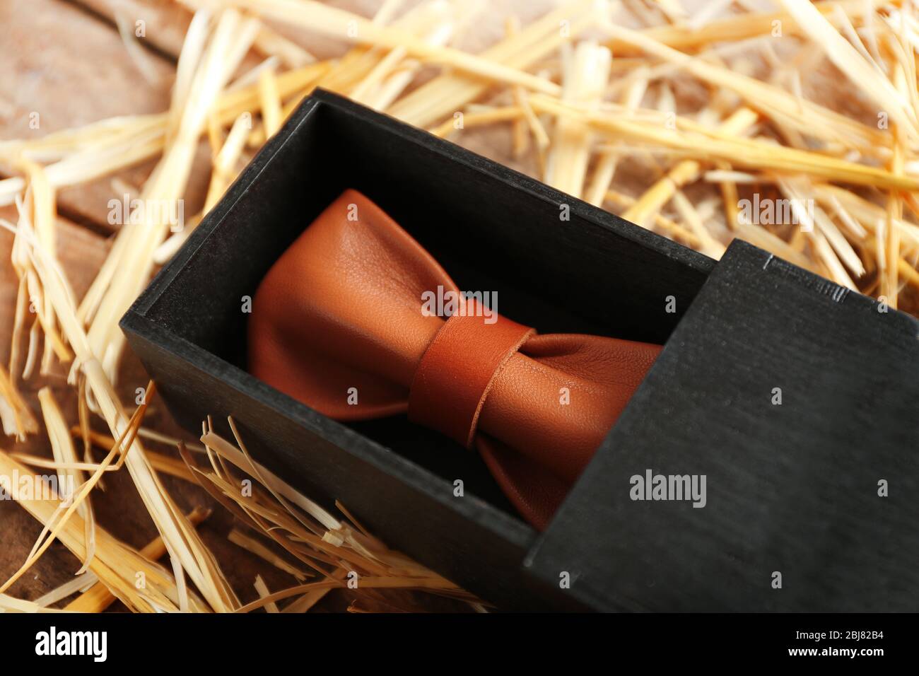 Brown leather bow tie in a special packaging on a thatch, close up ...