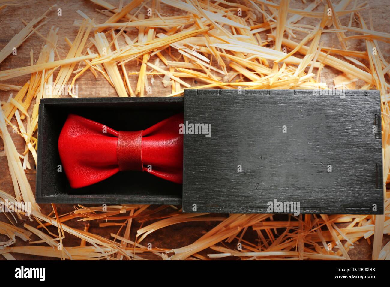 Red leather bow tie in a special packaging on a thatch, close up Stock ...