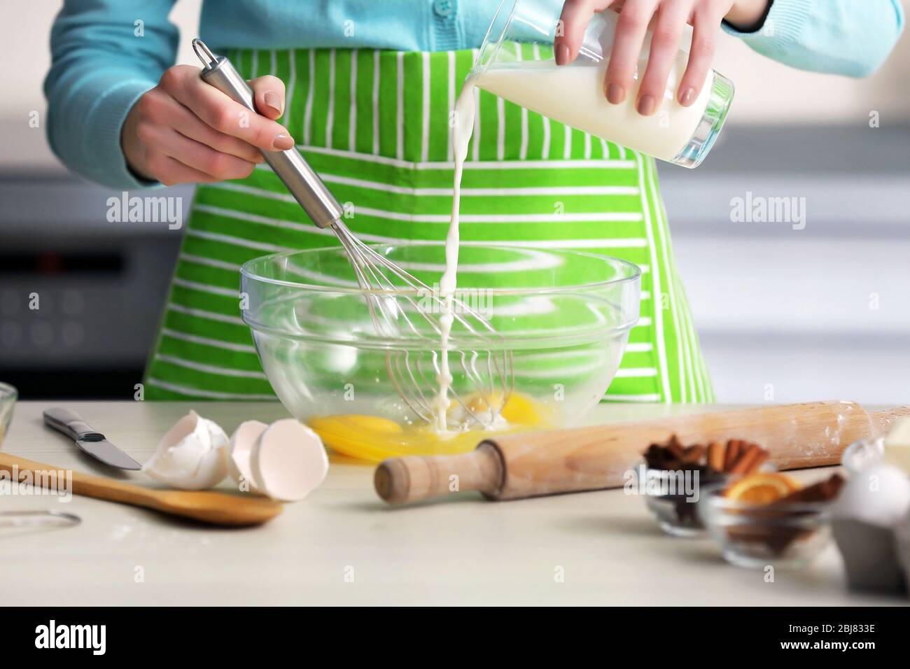 Young woman adding a milk to the egg mixture Stock Photo - Alamy