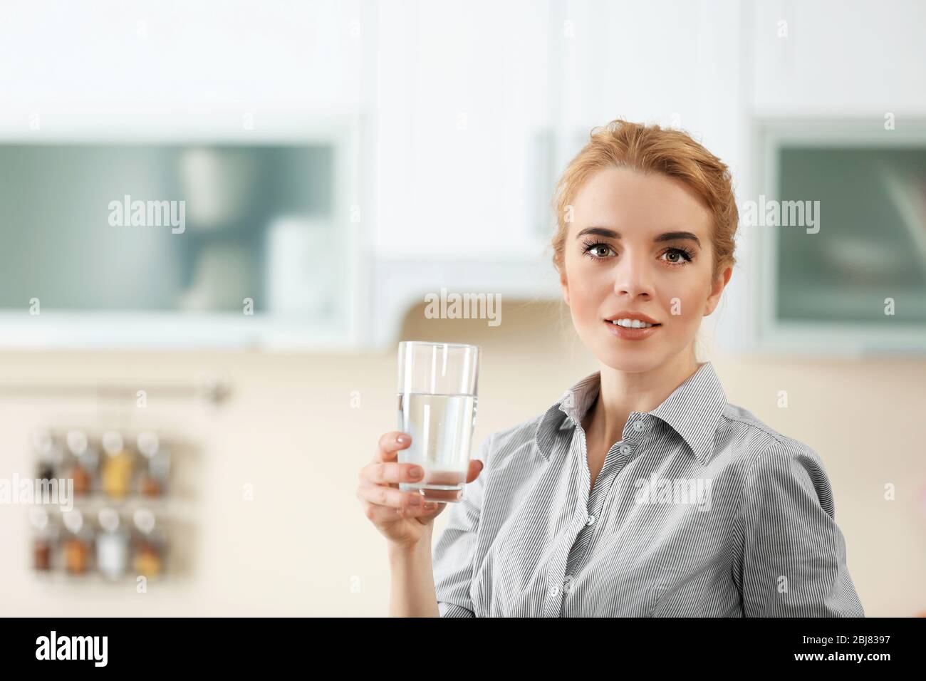 Young woman in the kitchen drinking water Stock Photo - Alamy