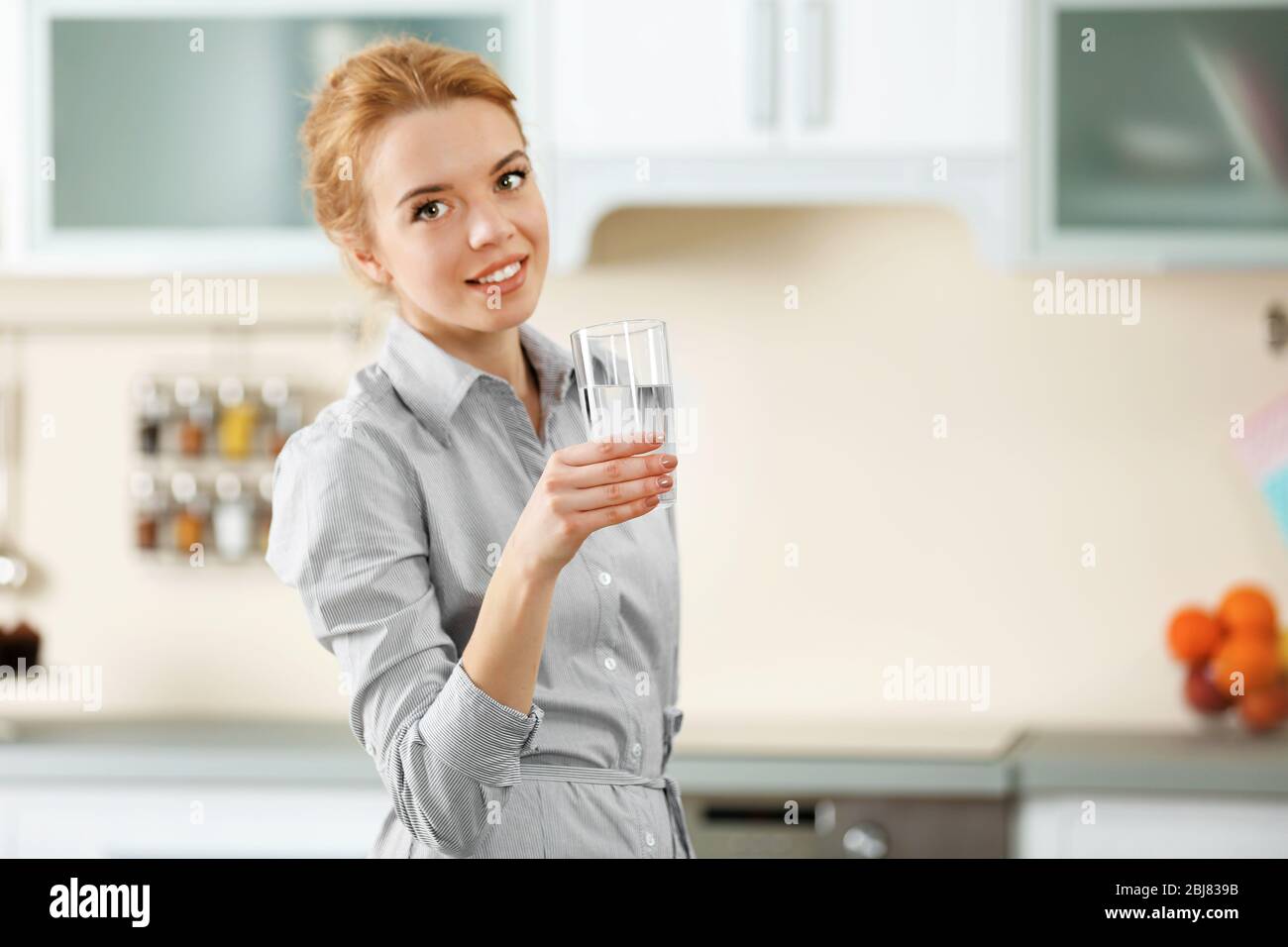 Young woman in the kitchen drinking water Stock Photo - Alamy