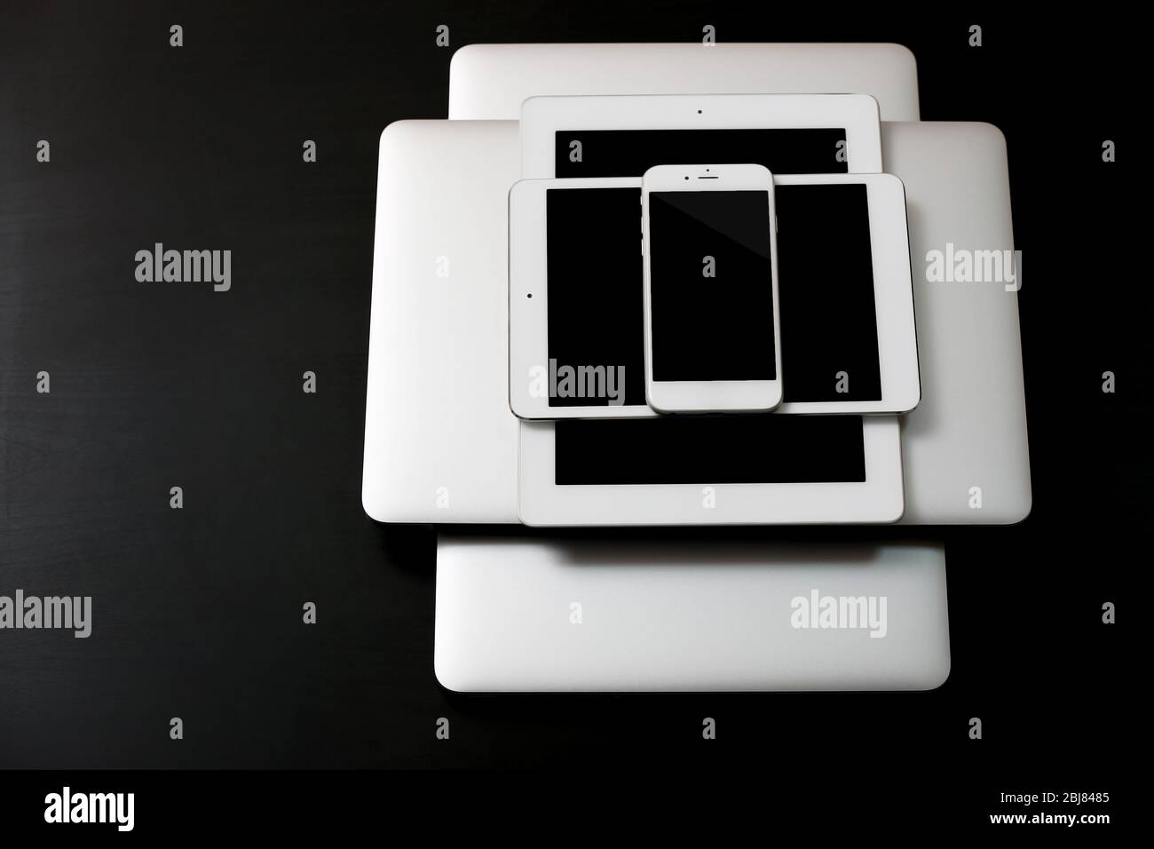 Stack of electronic devices on a dark desk Stock Photo - Alamy