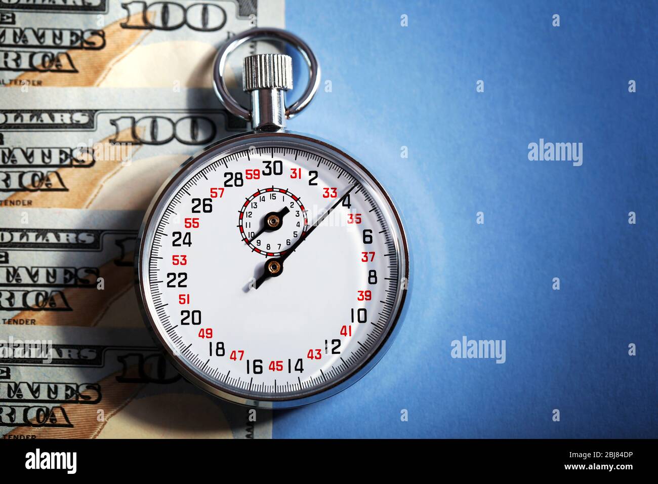 Stopwatch with dollar banknotes on blue background. Time is money ...