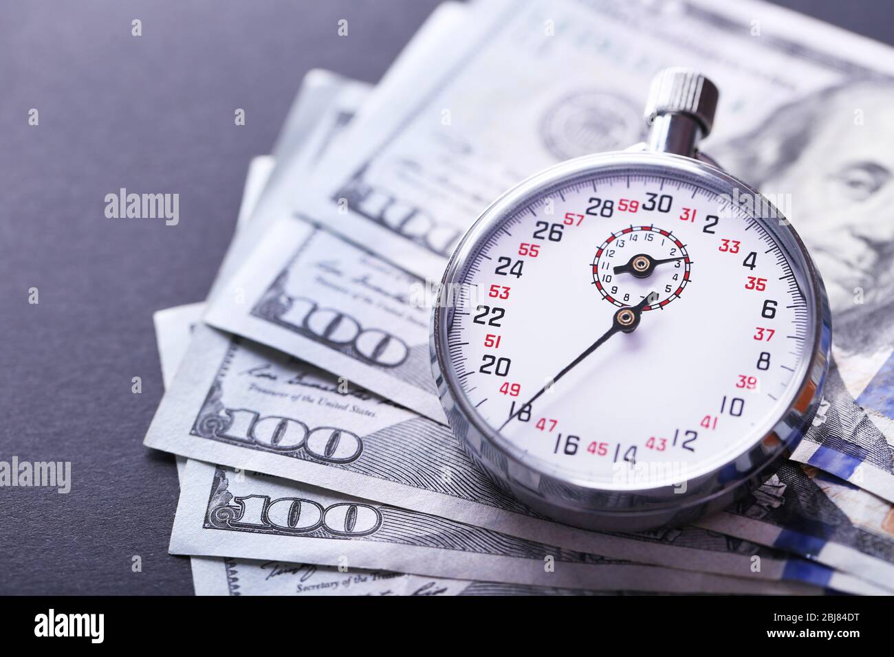 Stopwatch with dollar banknotes on black background. Time is money ...