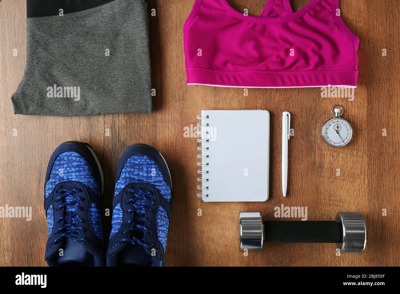 Athlete's set with female clothing, equipment and notebook on wooden ...