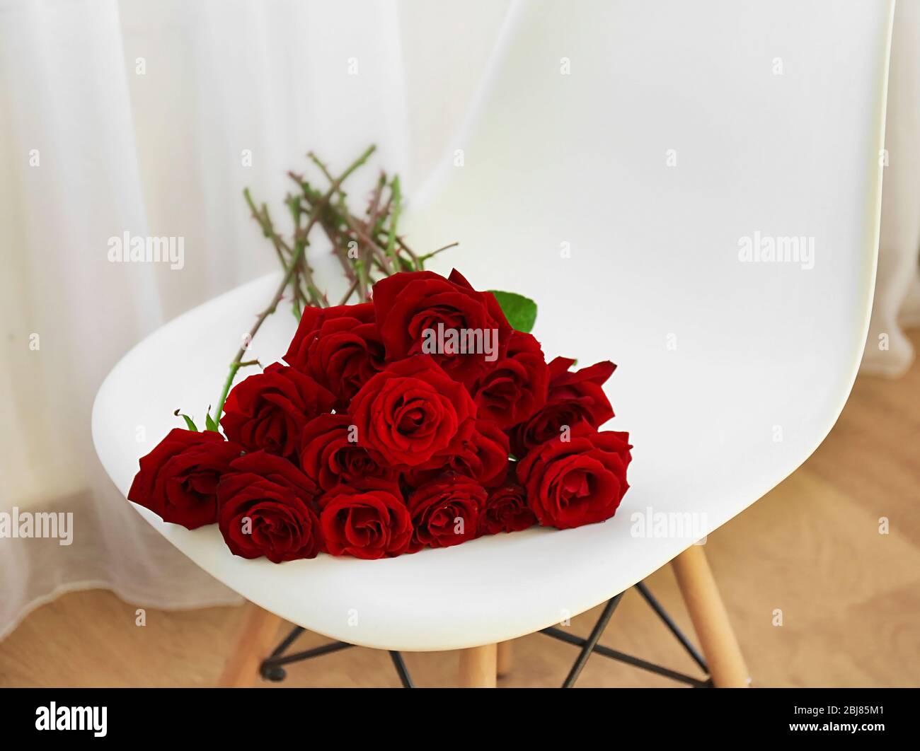 Red roses on chair beside window with curtain Stock Photo - Alamy