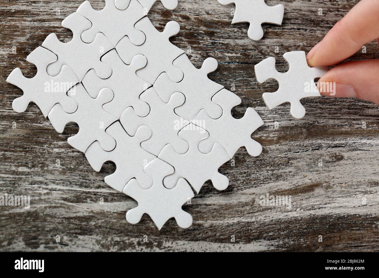 Woman playing with jigsaw puzzle on wooden table Stock Photo - Alamy