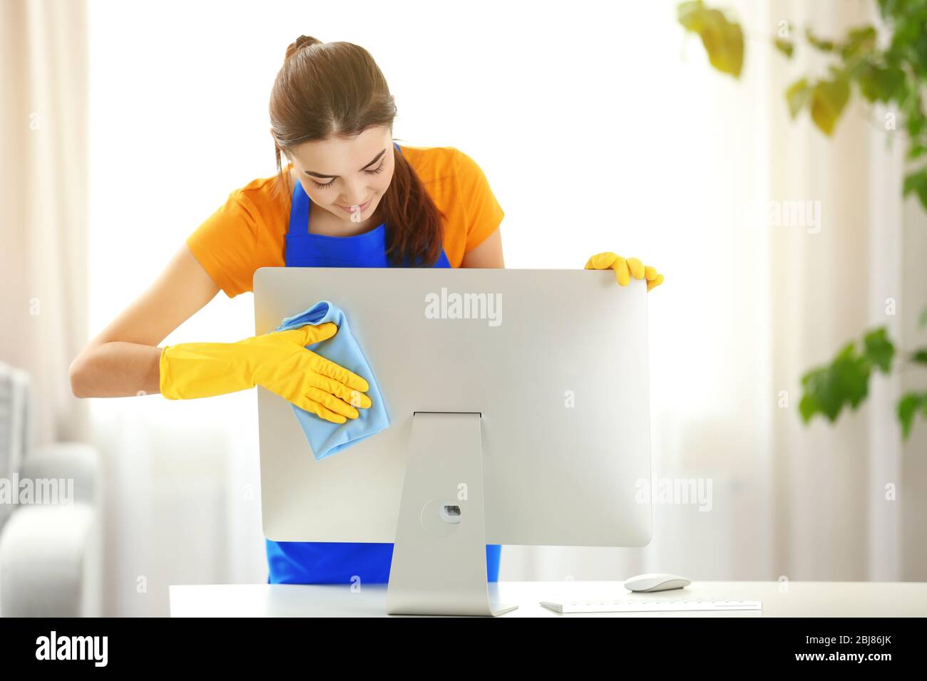 Young woman cleaning computer monitor at workplace in the office Stock ...