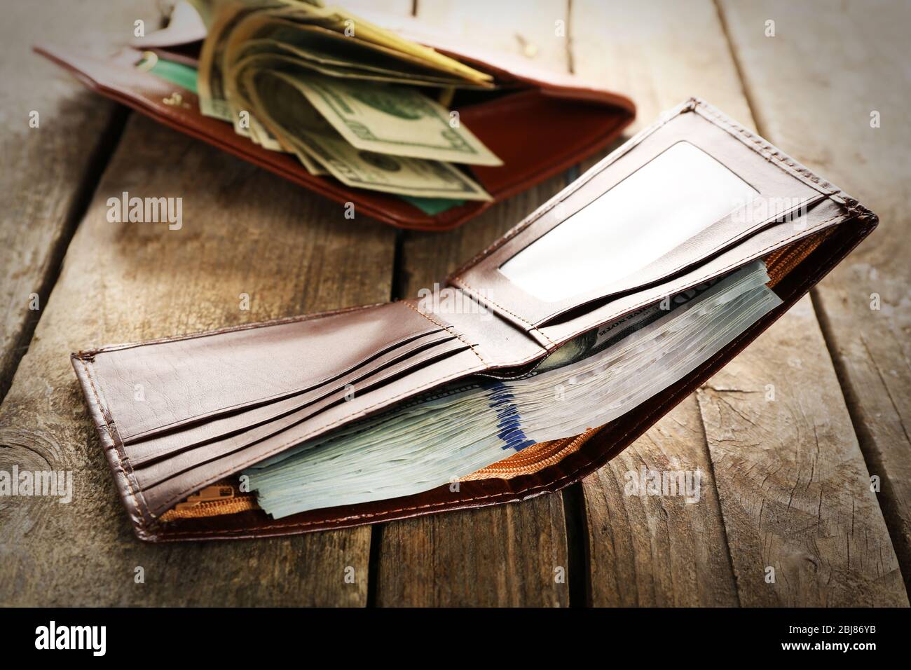 Brown leather wallet with money on wooden table Stock Photo - Alamy