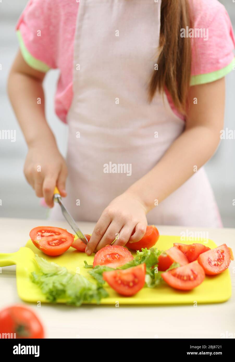 Little girl cutting vegetables for the salad in the kitchen Stock Photo ...