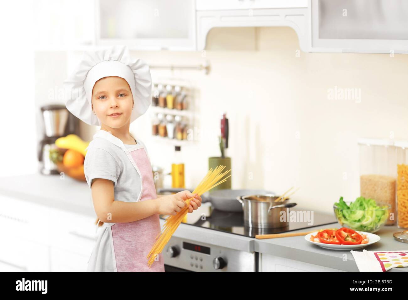 Little girl cooking spaghetti on the kitchen Stock Photo - Alamy