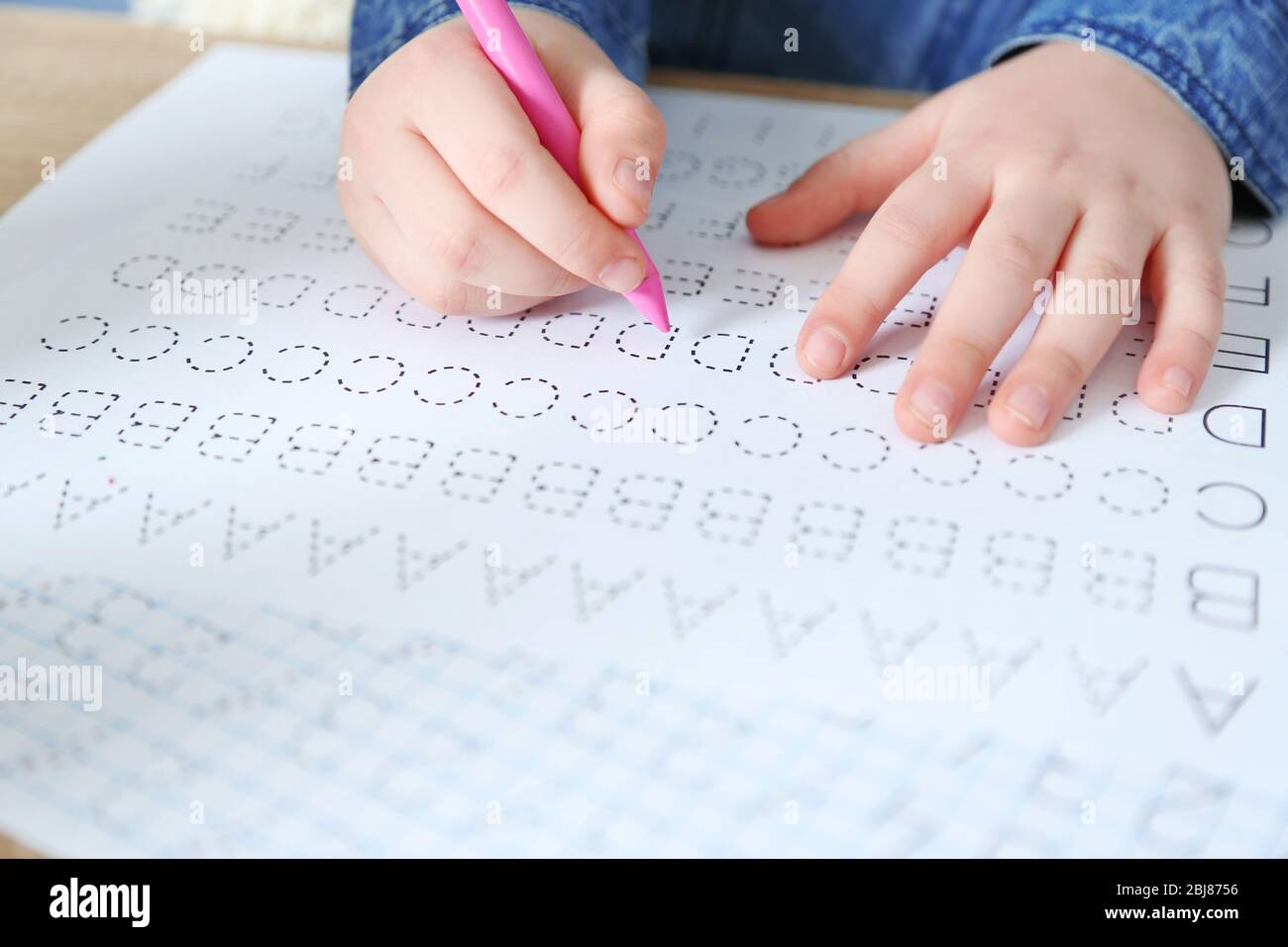 Little girl learning to write English letters at the table Stock Photo ...