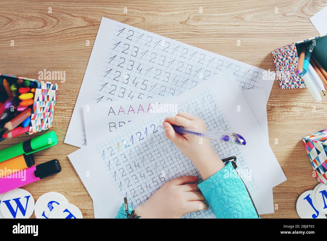 Little girl learning to write digits at the table Stock Photo - Alamy