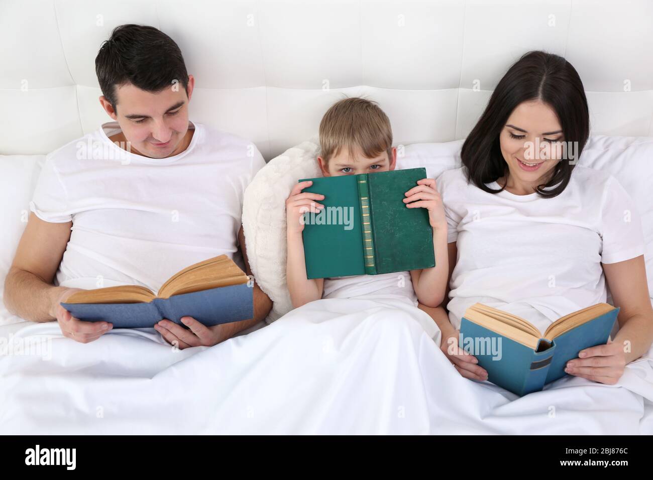 Family reading books in bed at home Stock Photo - Alamy
