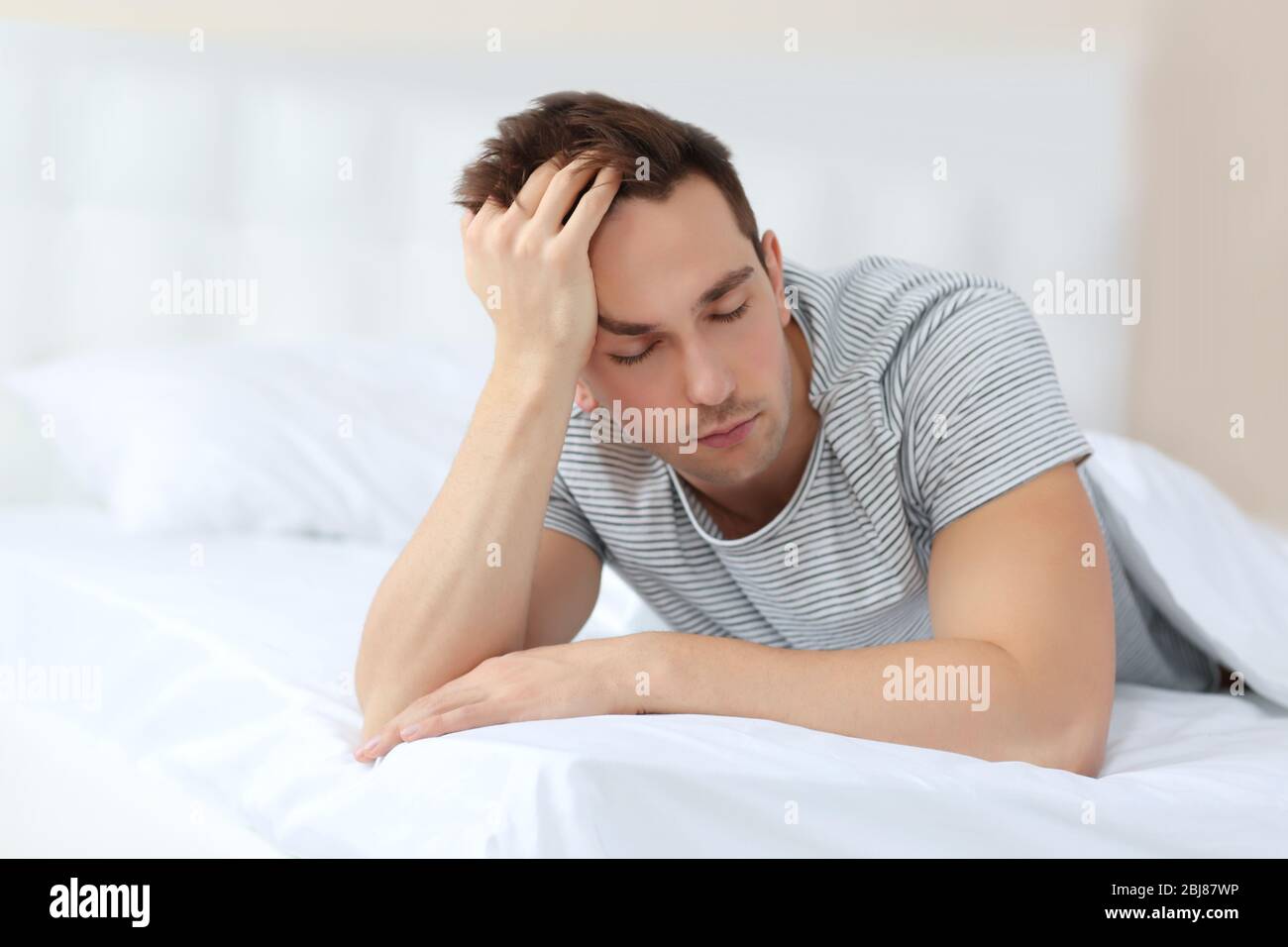 Sleepy young man in bed at home Stock Photo - Alamy