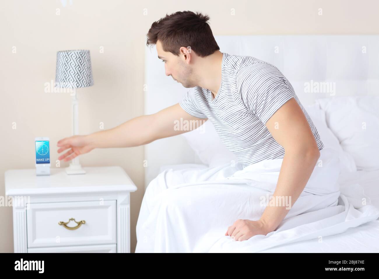 Young man reaching for his phone. Sleeping concept Stock Photo - Alamy