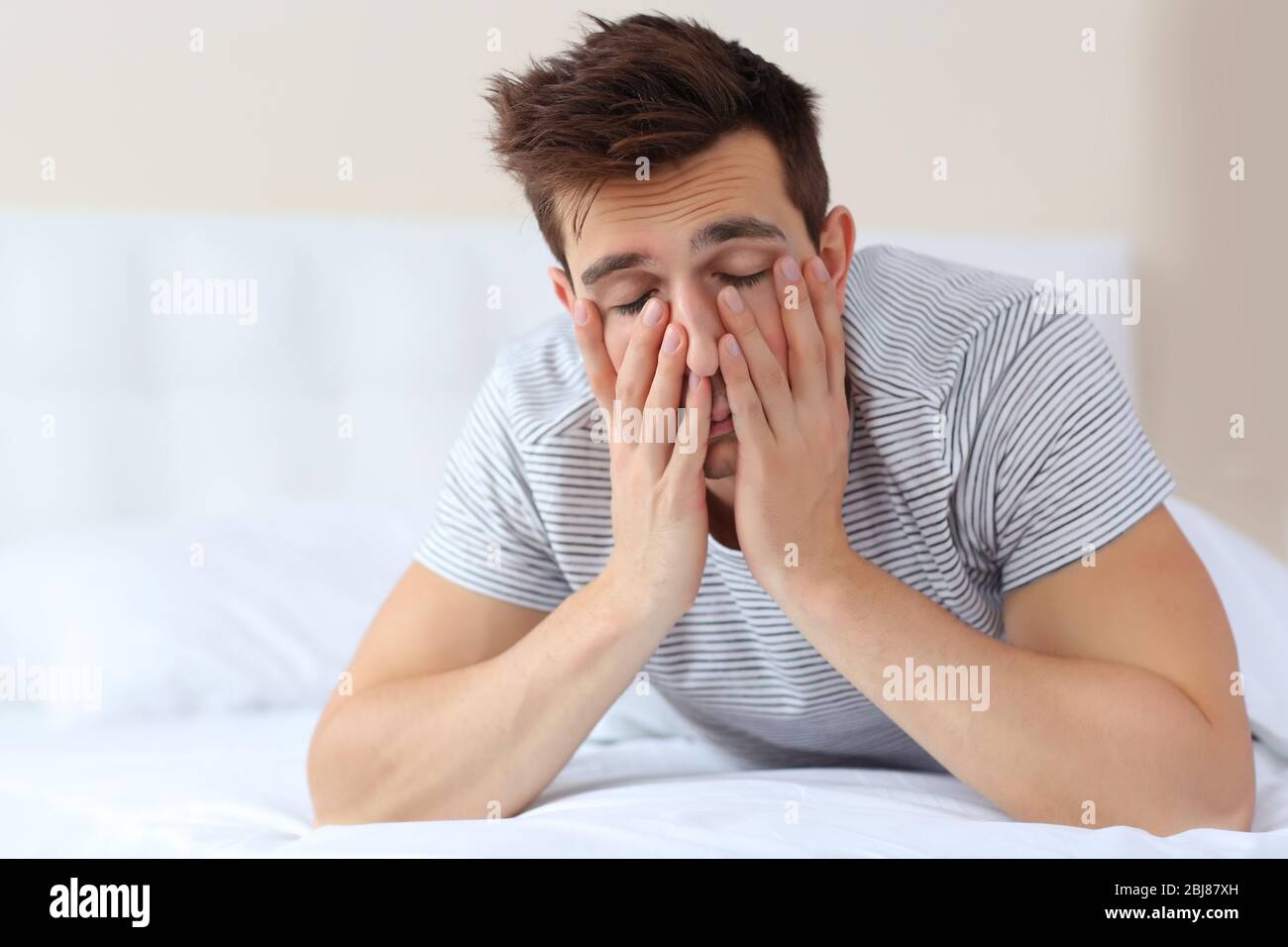 Sleepy young man in bed at home Stock Photo - Alamy