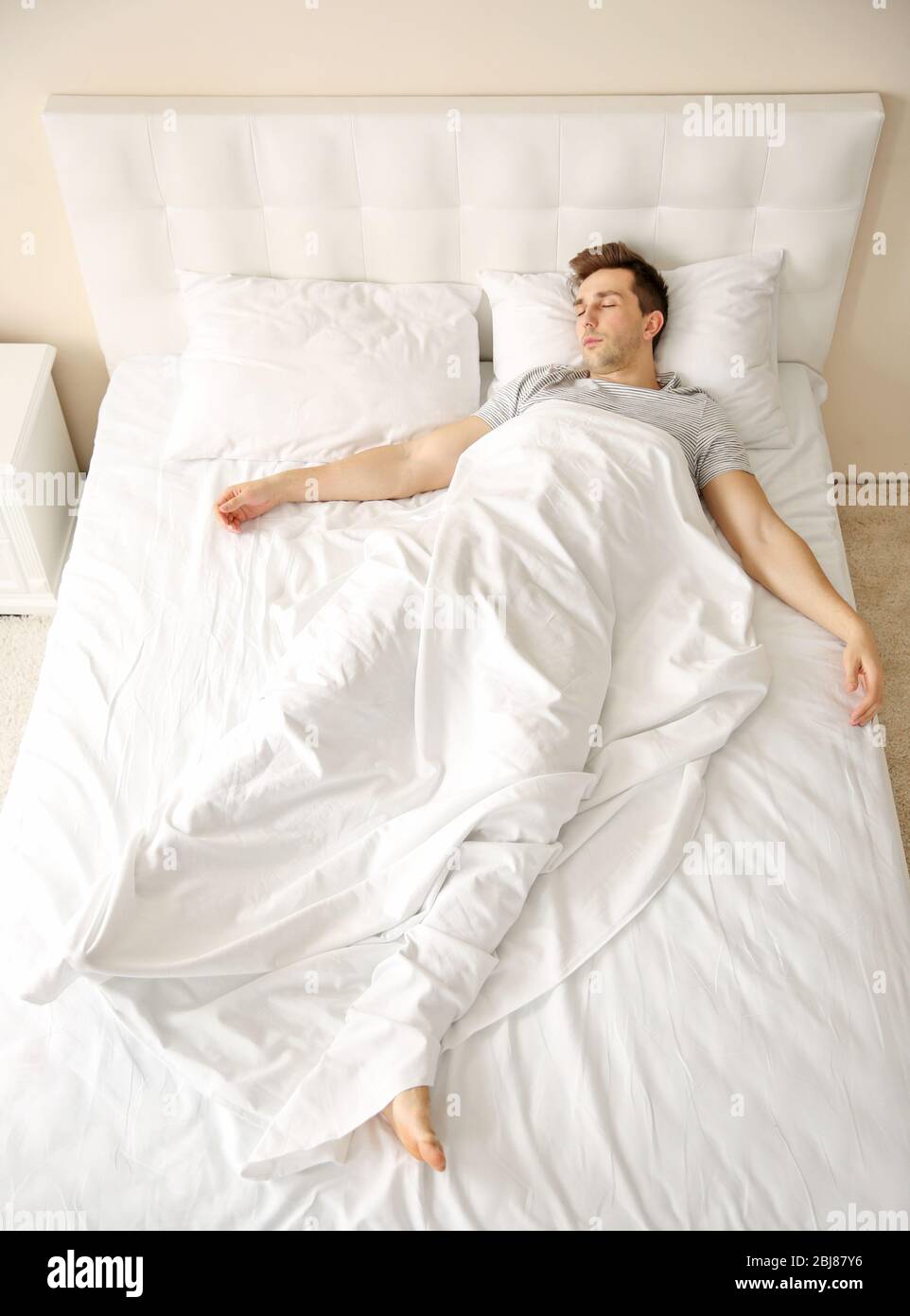 Young man sleeping alone in white big bed Stock Photo - Alamy