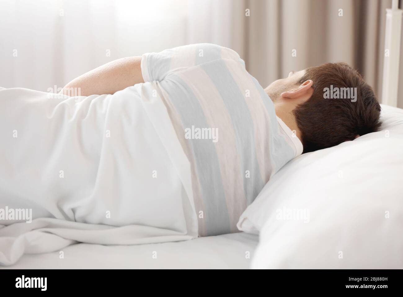 Young man sleeping on comfortable bed Stock Photo - Alamy