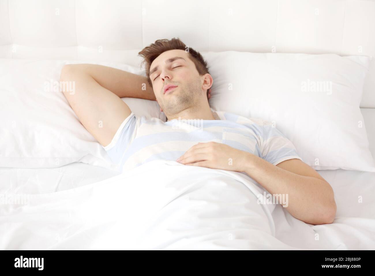 Young man sleeping on comfortable bed Stock Photo - Alamy