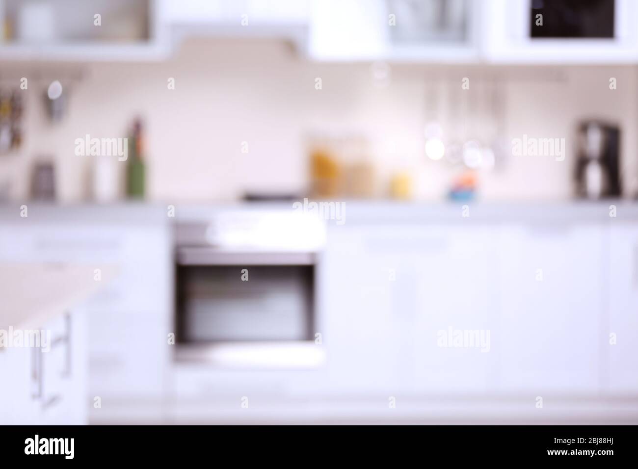 Blurred kitchen interior in light tones with white furniture and stove ...
