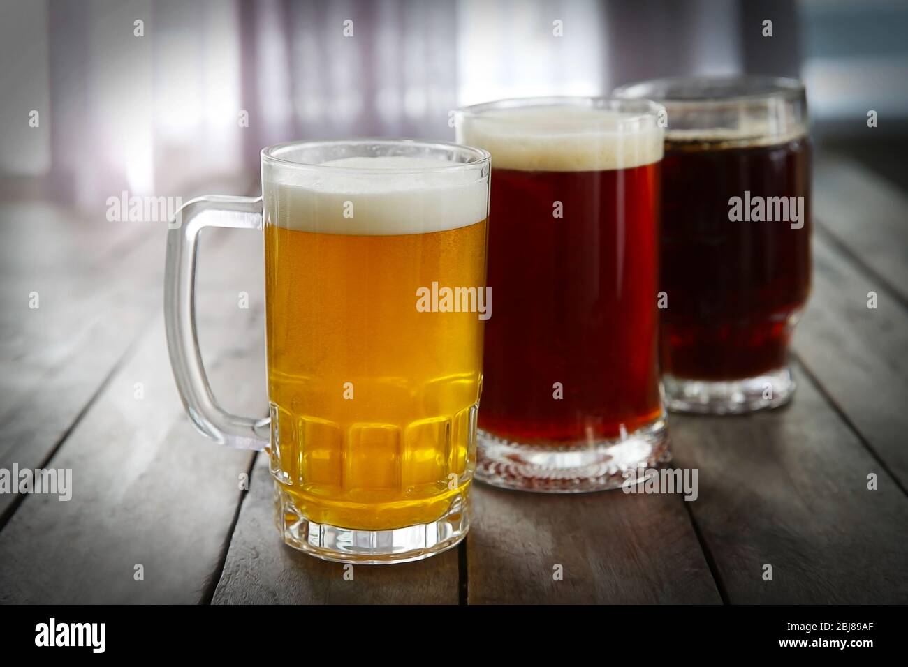 Glass mugs with different sorts of craft beer on wooden table Stock ...
